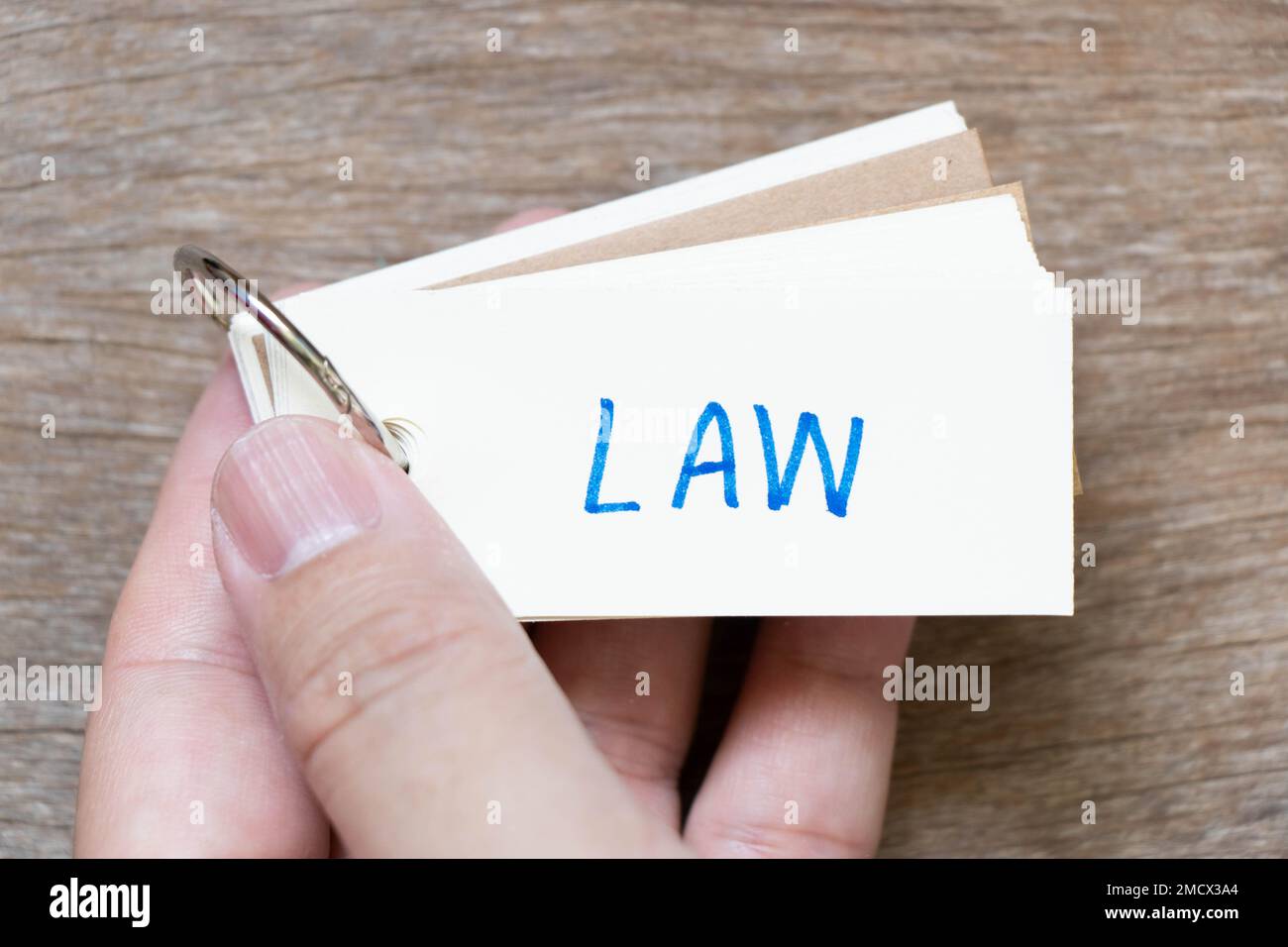 Hand hold flash card with handwriting in word law on wood background ...
