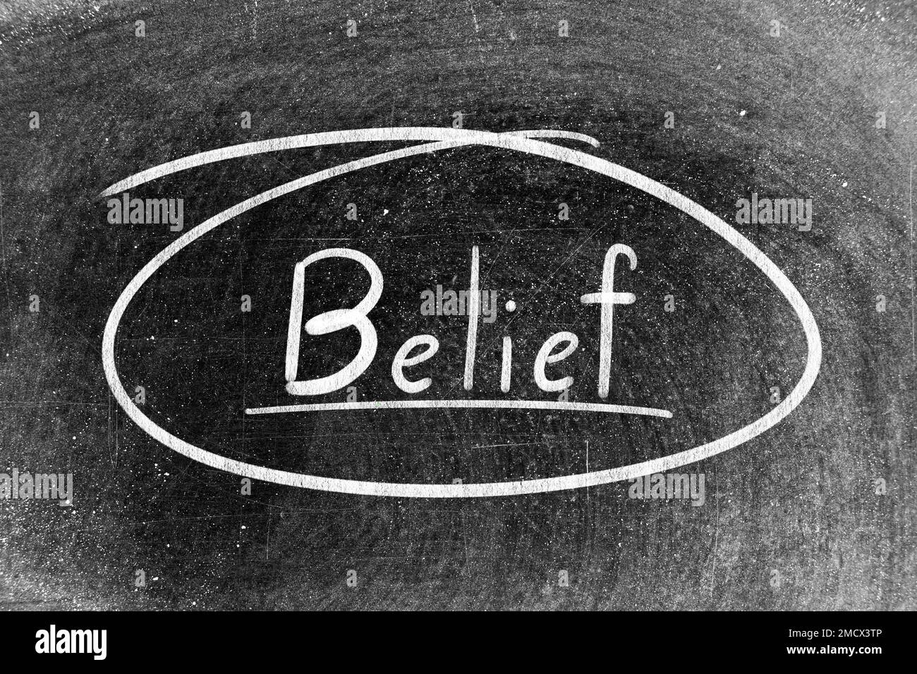 White chalk hand writing in word belief and circle shape on blackboard ...