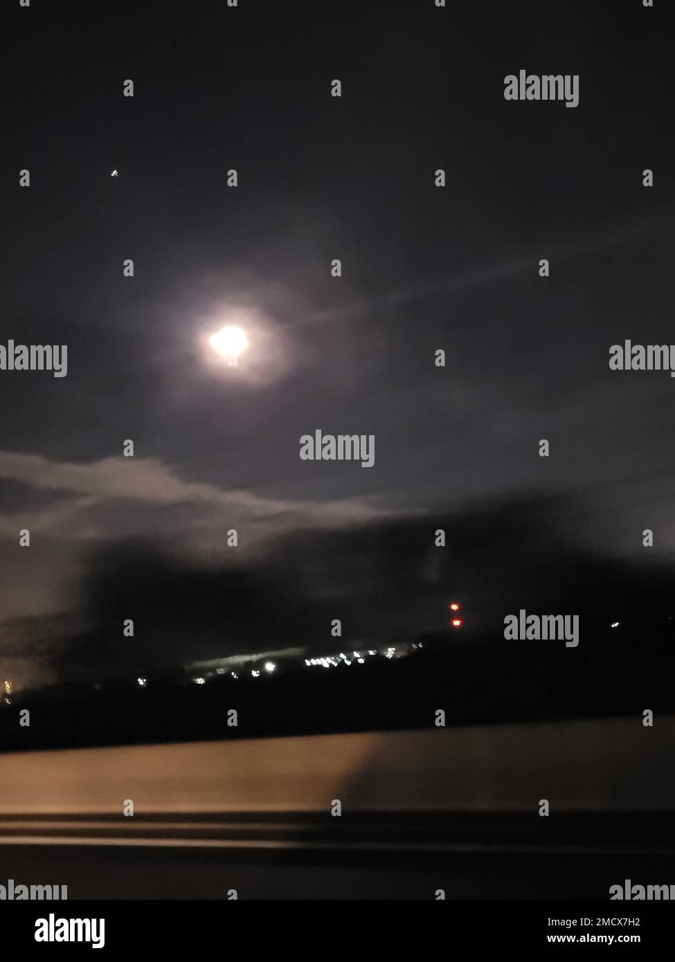 A vertical long exposure shot of with a disk of the moon in the night ...