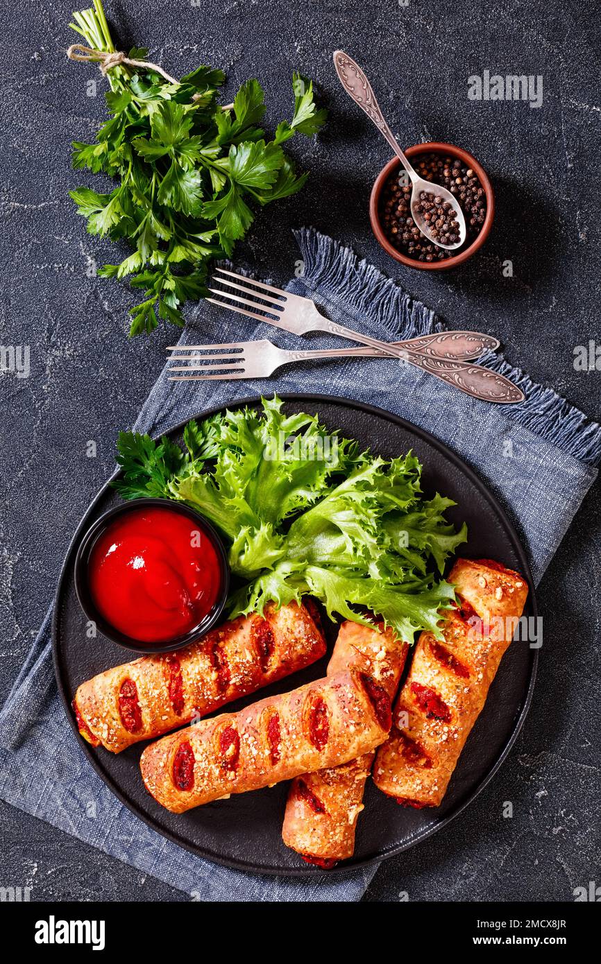 chorizo and semi-dried tomato puff pastry rolls on black plate with ...