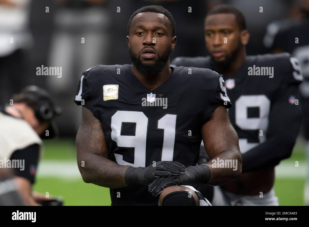 Las Vegas Raiders defensive end Yannick Ngakoue (91) with his helmet off stretched before ...