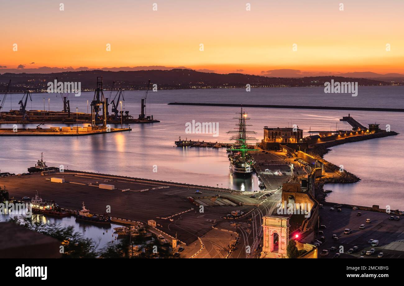 An aerial view of an illuminated port with ships under bright yellow ...