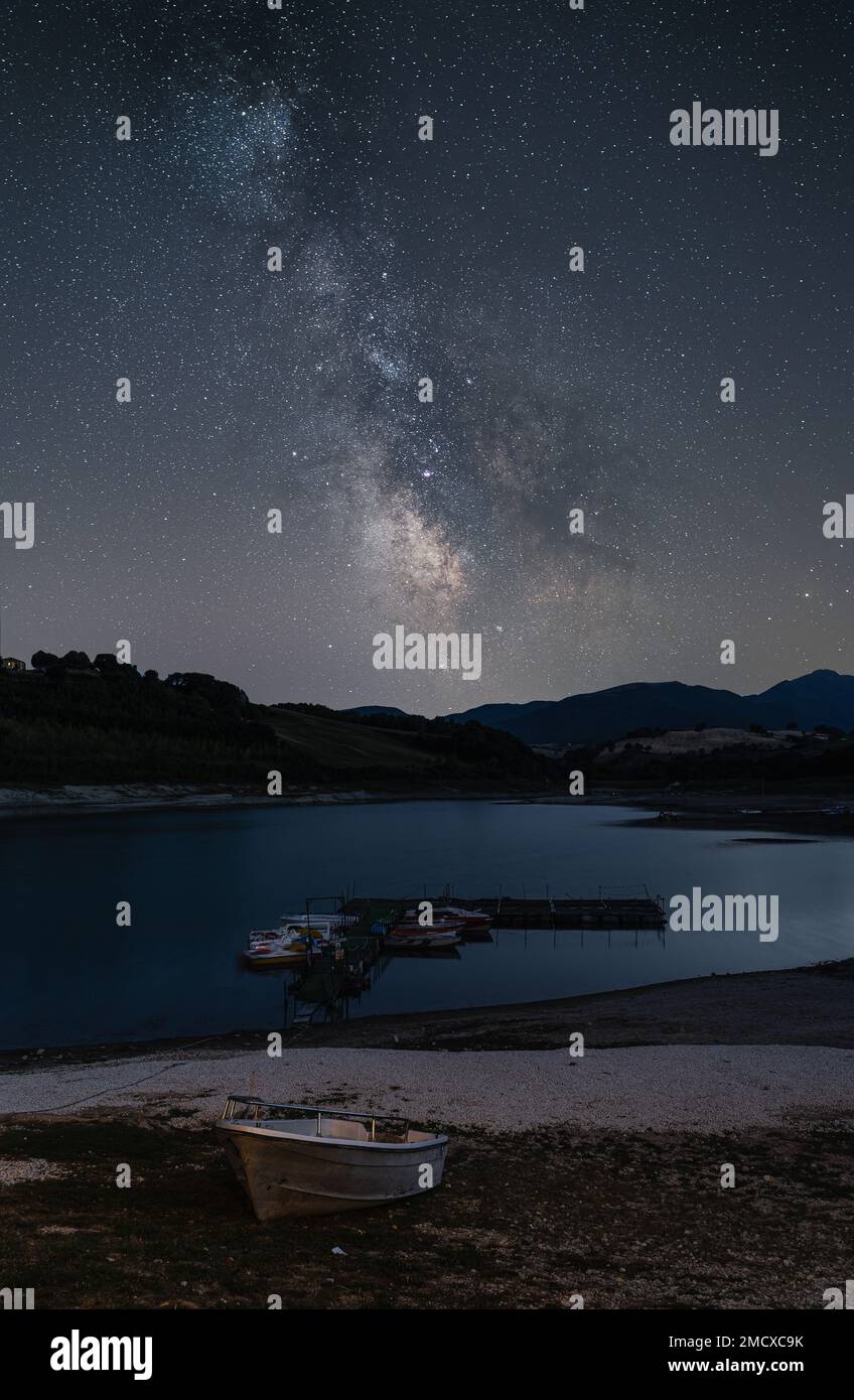 A breathtaking view of starry night sky over a lonely boat on the sandy ...