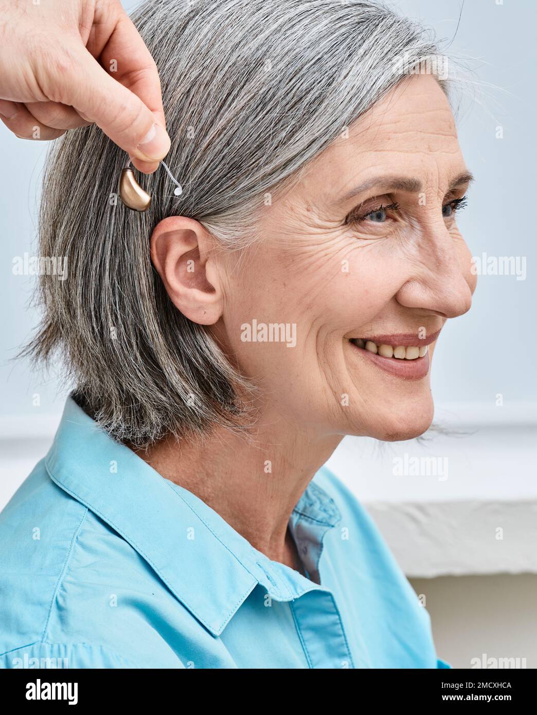 doctor audiologist applying hearing aid to senior woman's ear. Hearing ...