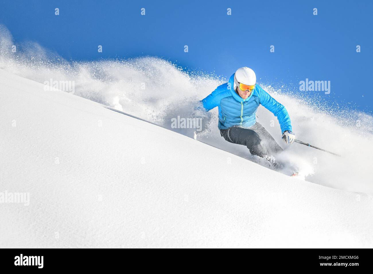 A skier on a carving turn in deep powder off-piste while free-riding ...