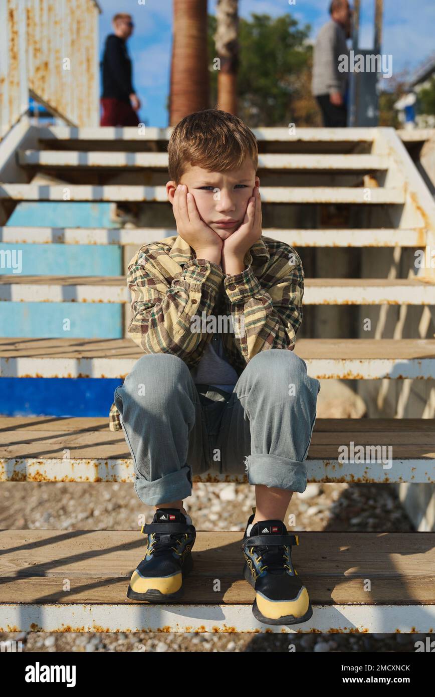 Child sitting on the steps. Portrait of handsome kid boy wearing casual ...