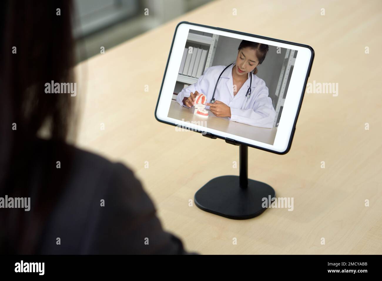 Back view of woman in suit have webcam conference on tablet computer ...