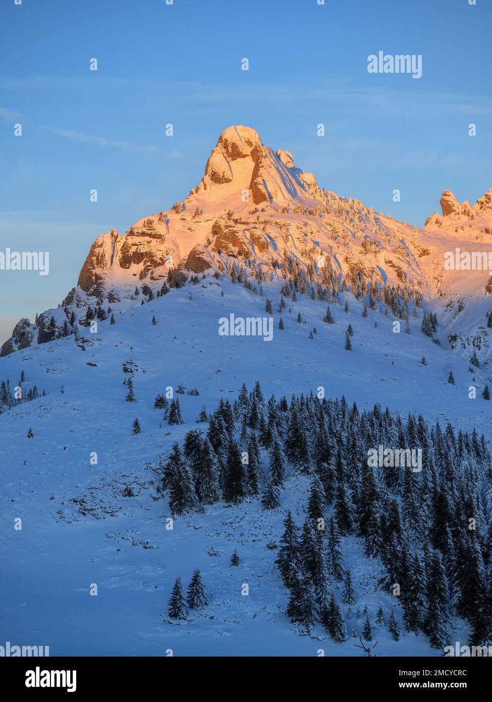 Mountain peak with sharp edges in warm sunrise warm light. Cold winter ...