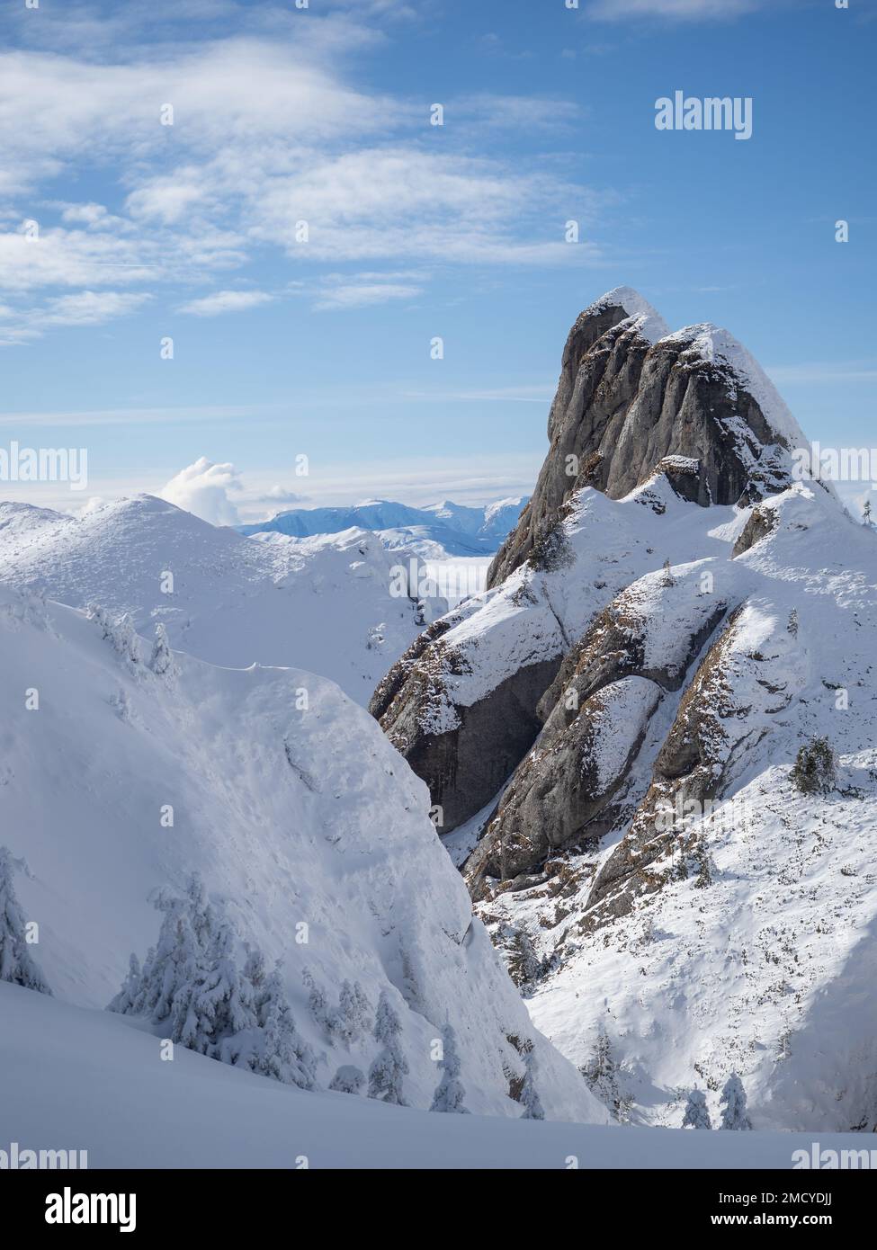 Aerial view of distant mountain peaks above clouds in clear sunny blue ...
