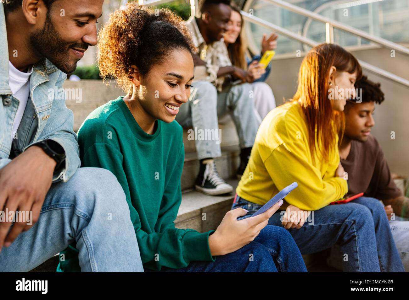 Young group of diverse people using mobile phone outdoor Stock Photo - Alamy