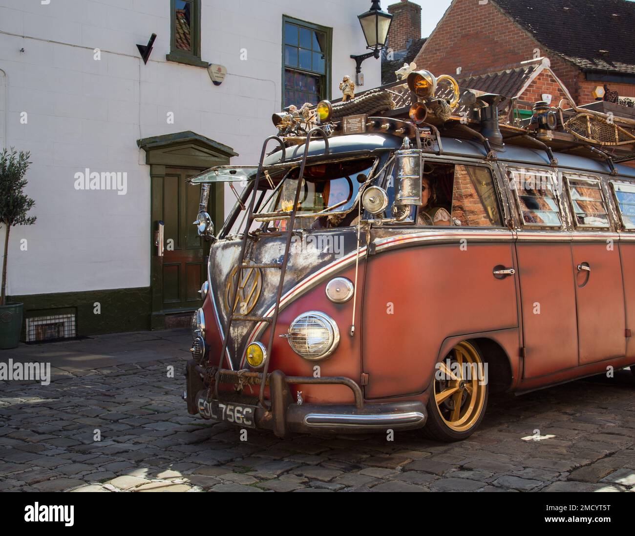 A customised Volkswagen camper van travelling on a cobbled road ...