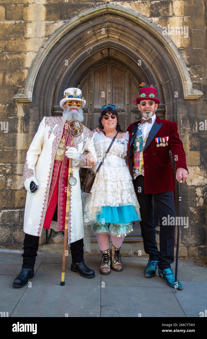 A group of very smartly dressed steampunks standing in front of an old ...