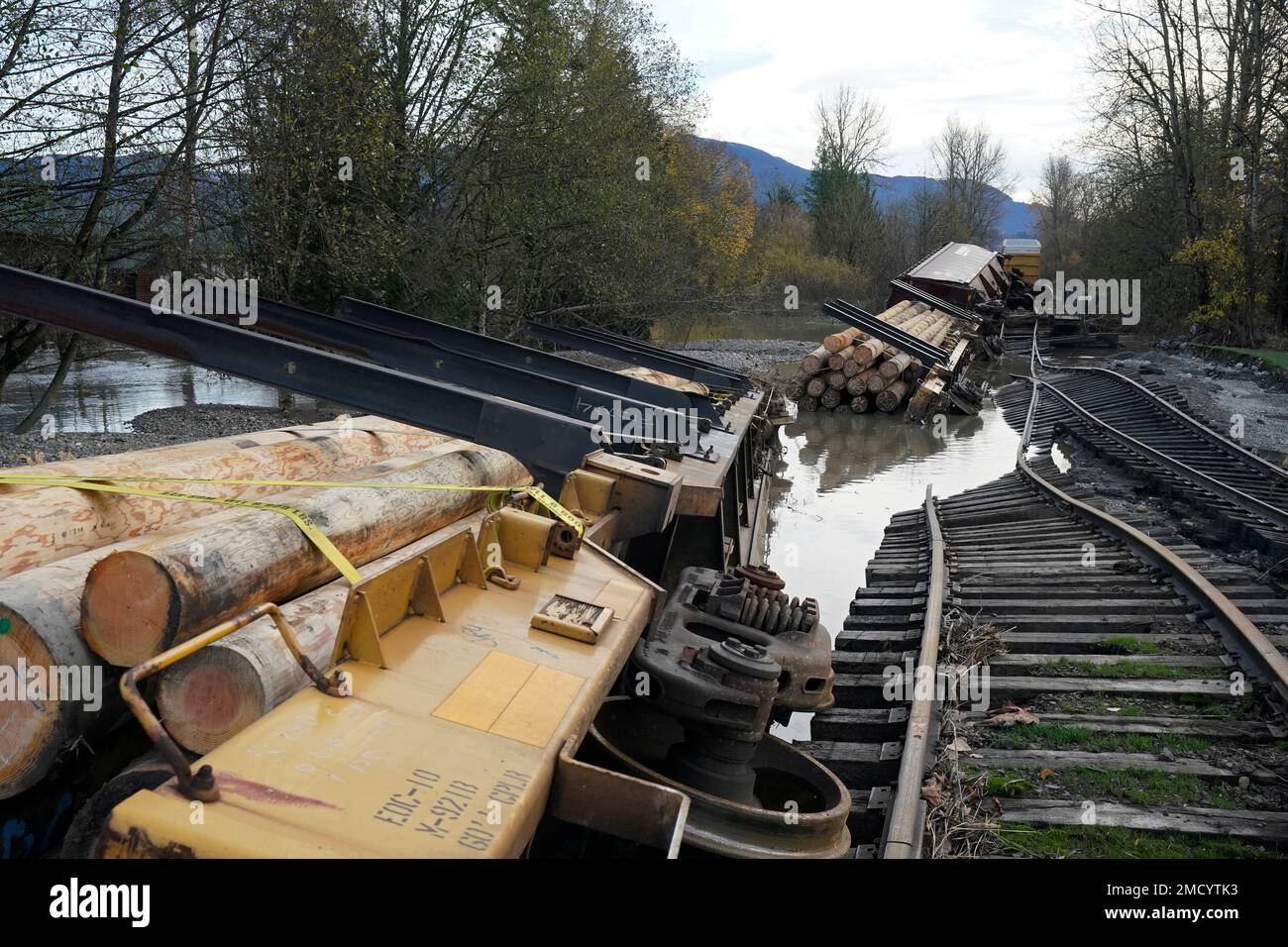Railroad cars derailed by flooding lie on their side near tracks at a ...