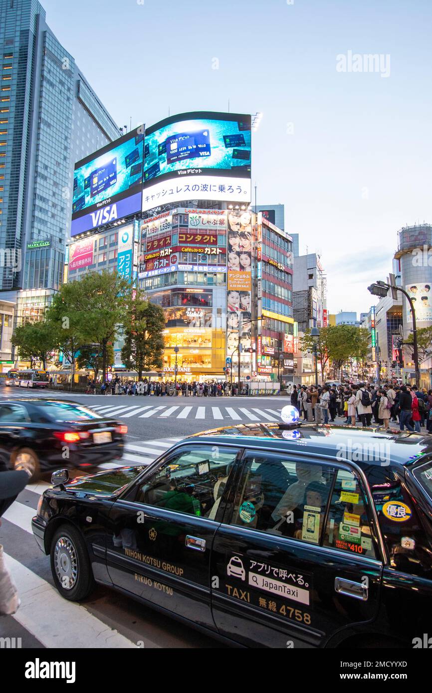 Tokyo. The famous landmark Shibuya scramble crossing, with taxi in foreground, people waiting to ...