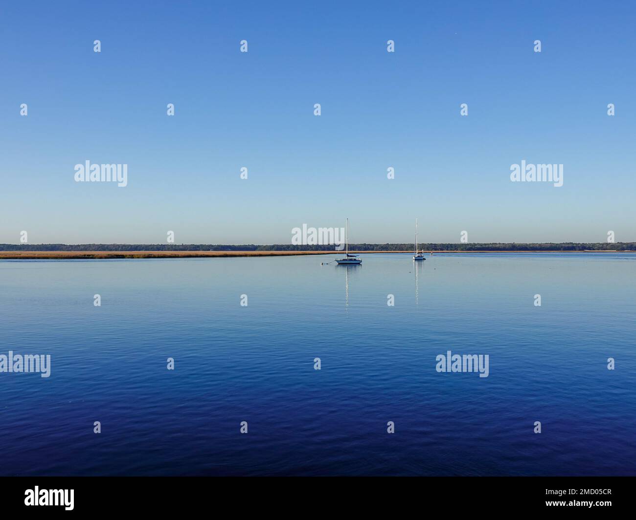Boats moored in the middle of the calm water of St. Marys River, early ...