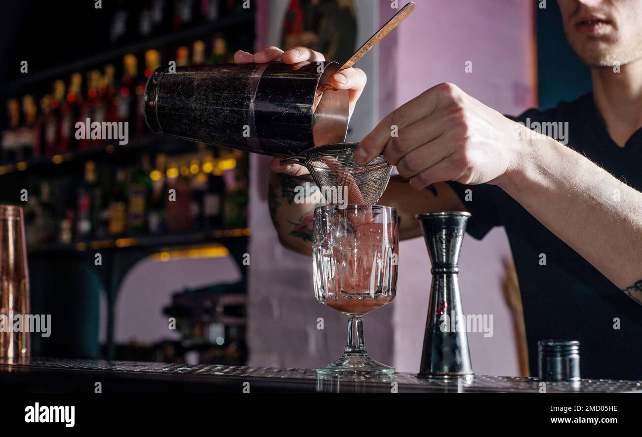 Barkeeper pouring ready pink smoothie cocktail Bartender makes a ...