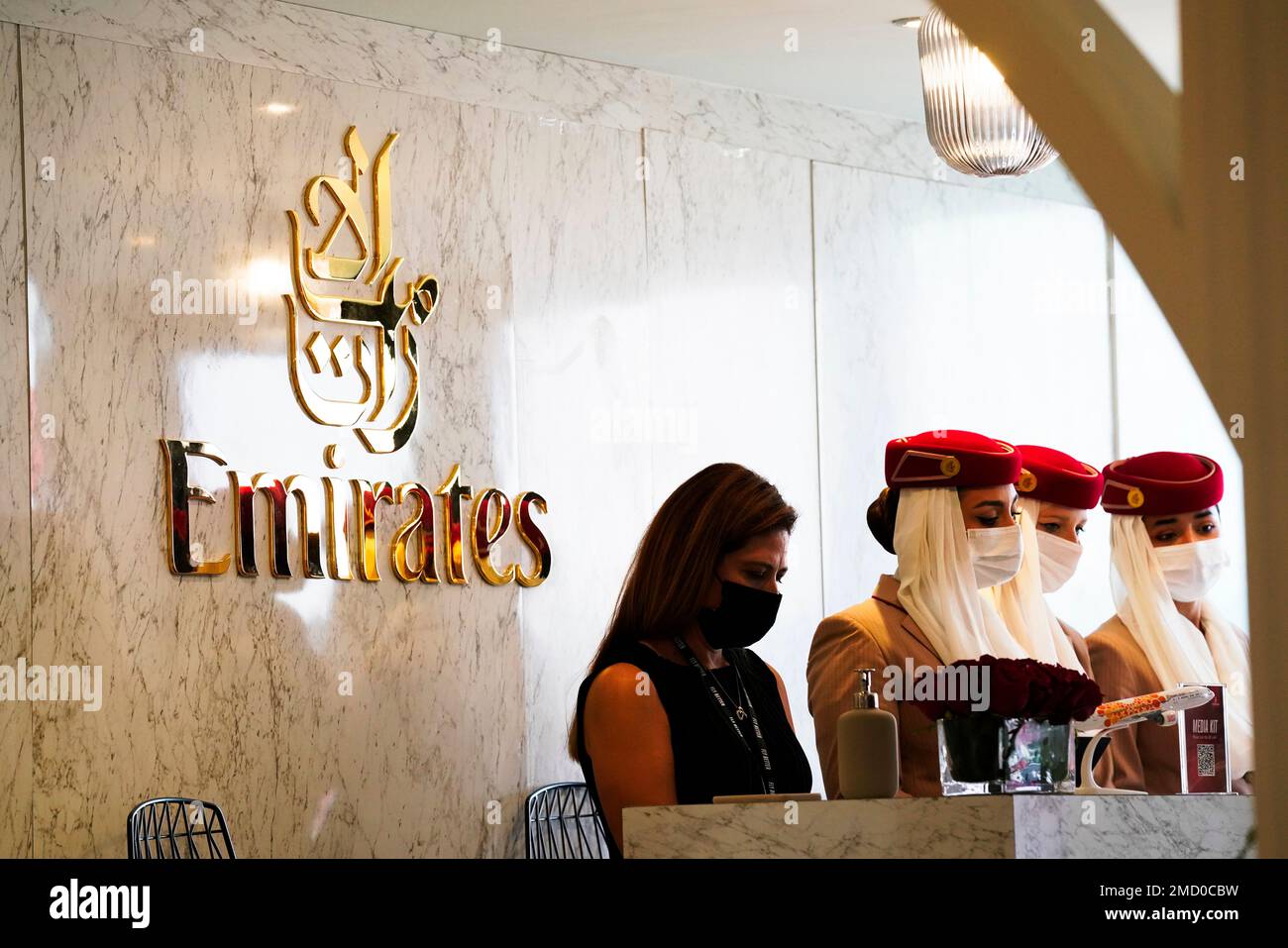 Attendants stand the logo of the long-haul carrier Emirates at the ...