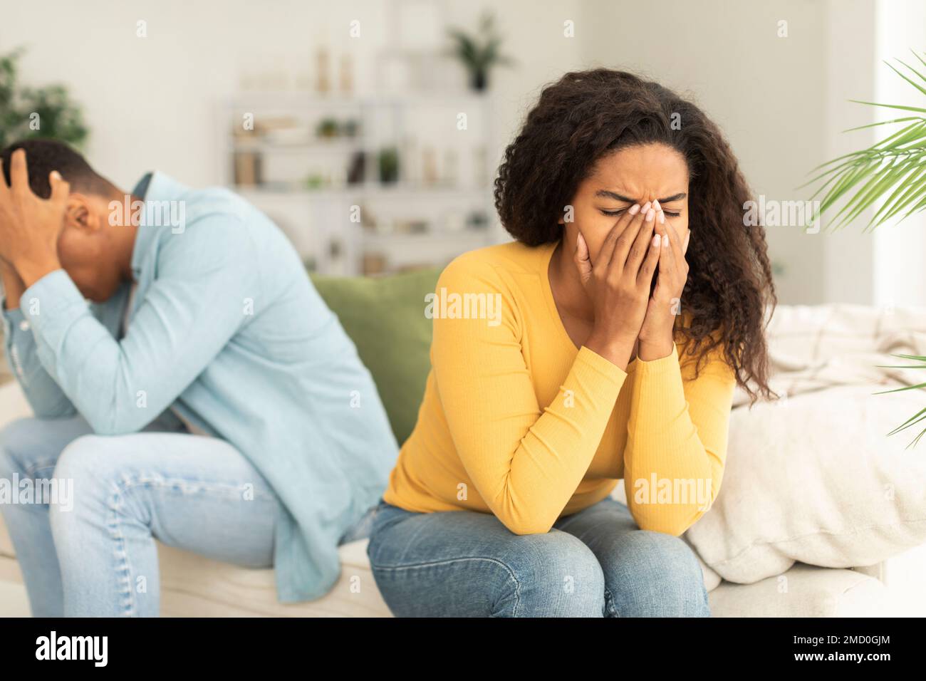 Sad crying young african american woman ignores offended man after quarrel, sit on sofa, think ...
