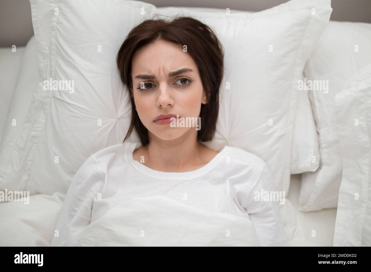 Unhappy young woman lying in bed at home, copy space Stock Photo - Alamy