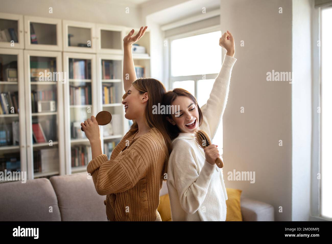 Happy excited european young superstar ladies have fun, sing song at ...