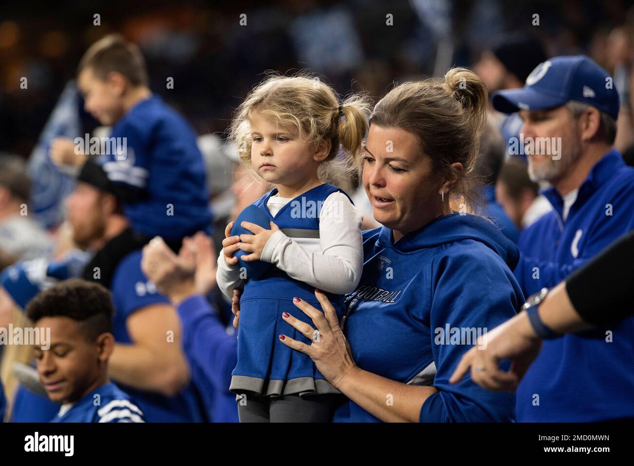 A young fan holds a football in the stands during an NFL football game ...