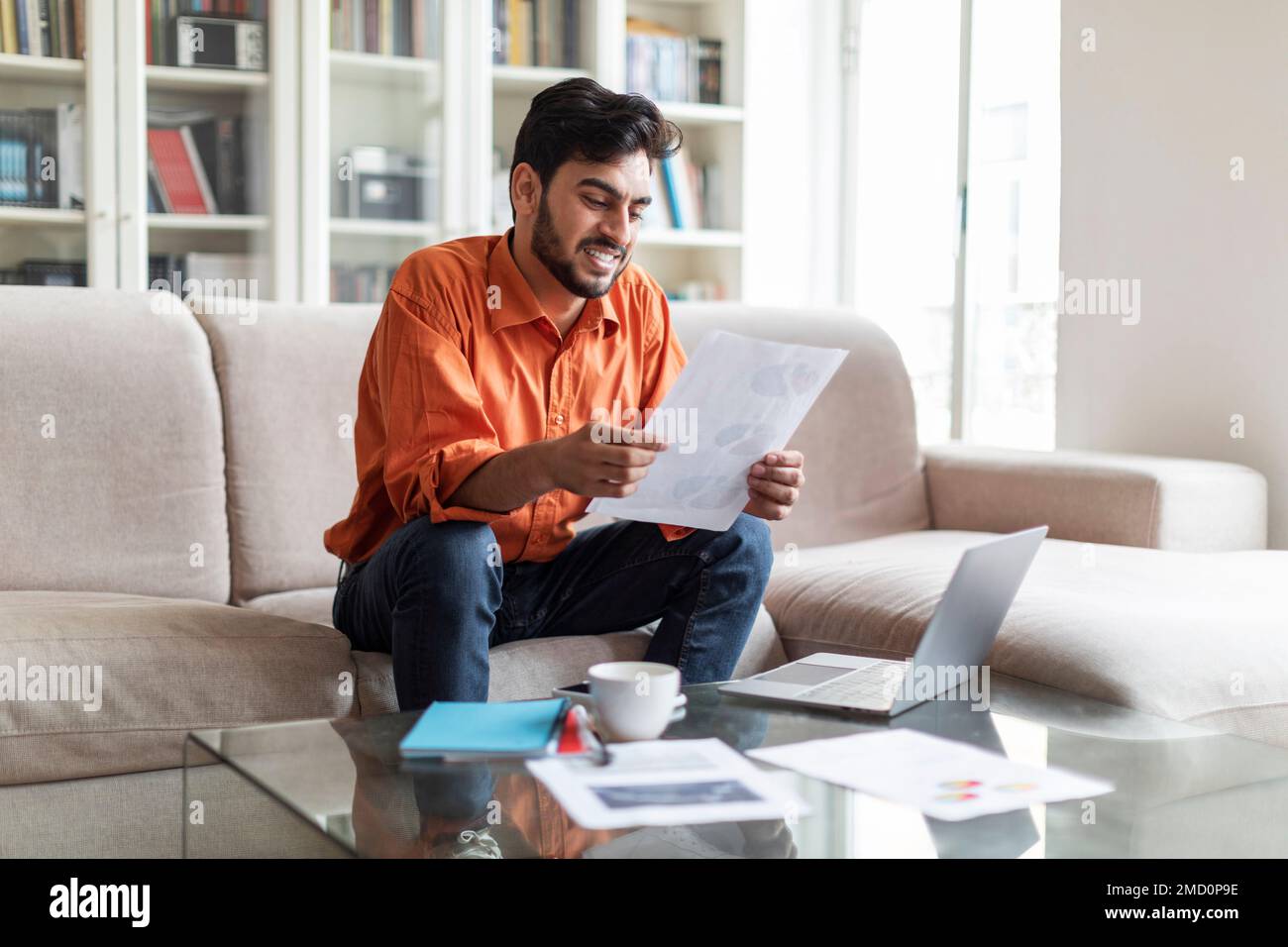 Happy arab guy working from home, checking papers Stock Photo - Alamy