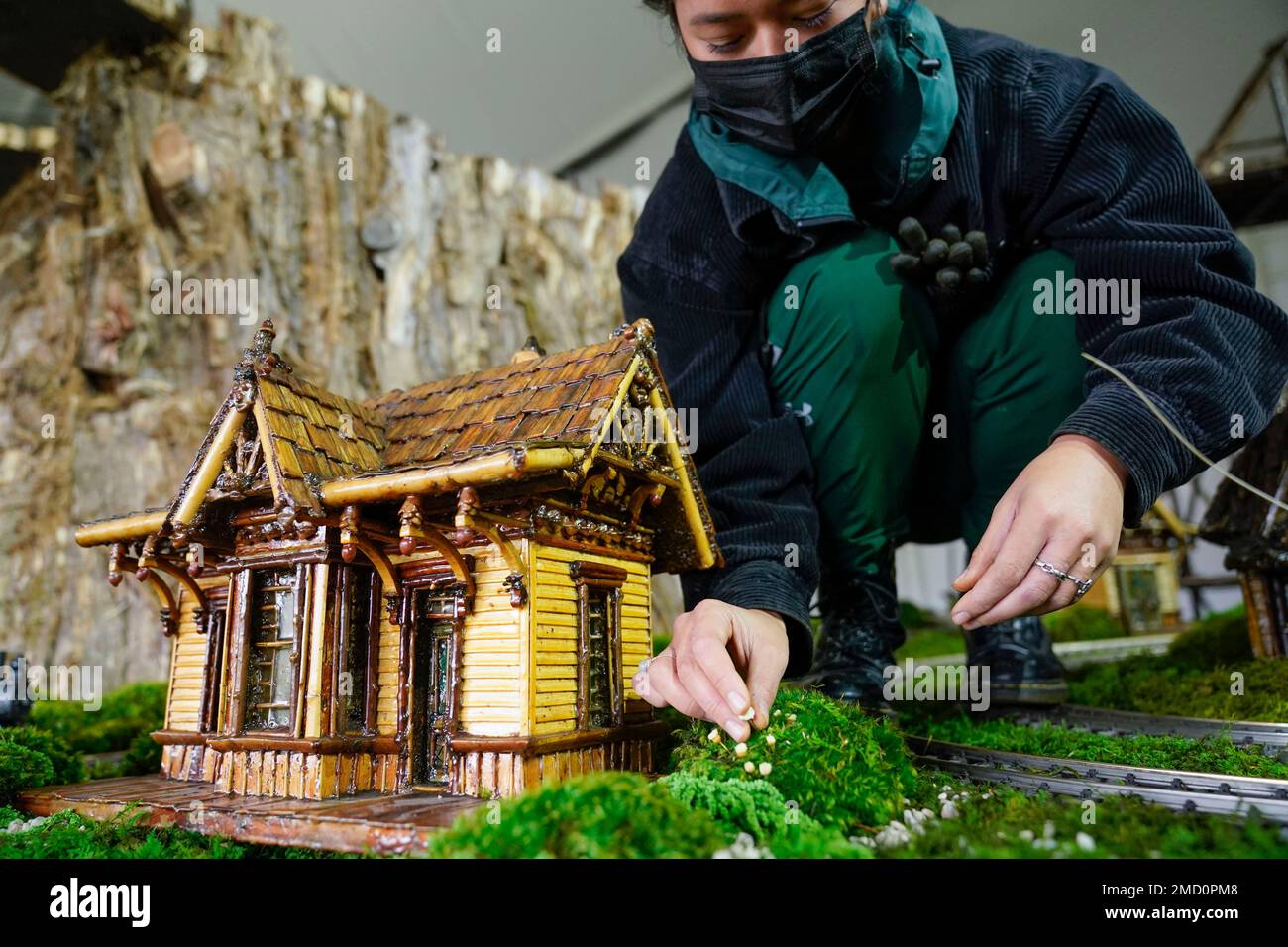 Margeaux Lim fills in the landscaping around a miniature house as part ...