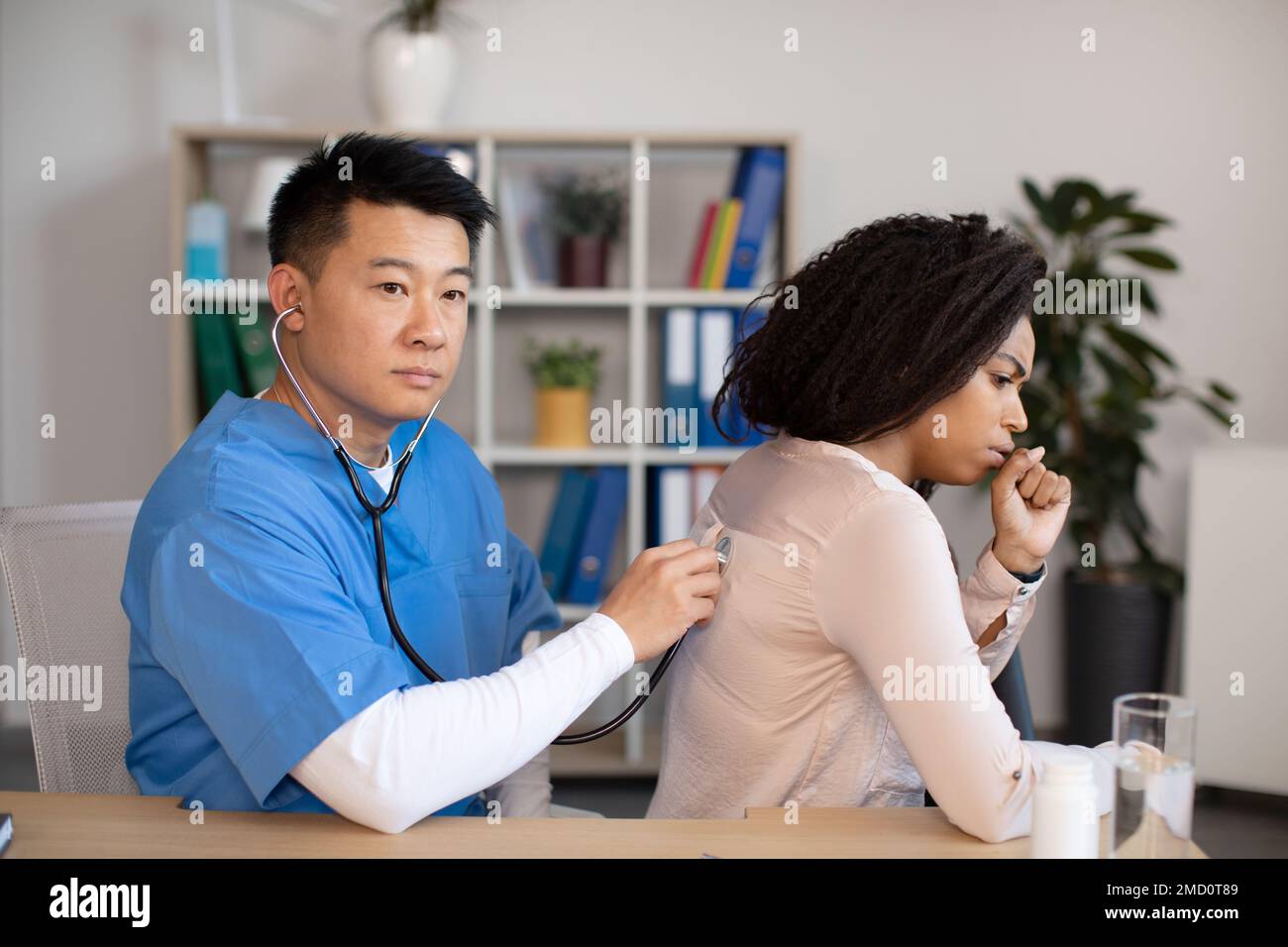 Serious mature korean doctor listens to breathing from coughing black ...