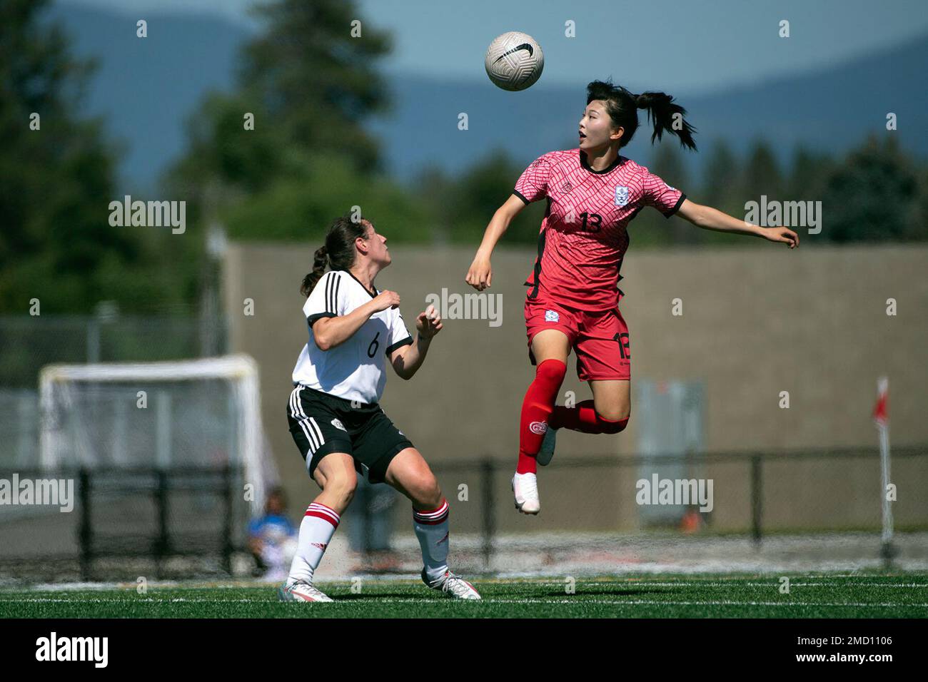 Korea's Jeongmin Lee leaps for a header above Canada’s Katie MacAskill ...