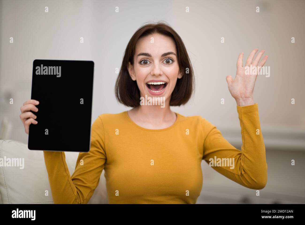 Excited young woman showing tablet with black screen Stock Photo - Alamy