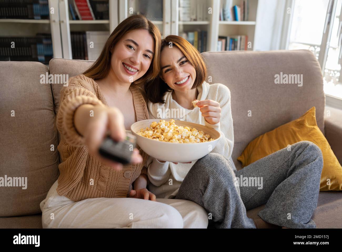Happy european young women with remote control eat popcorn, have fun ...