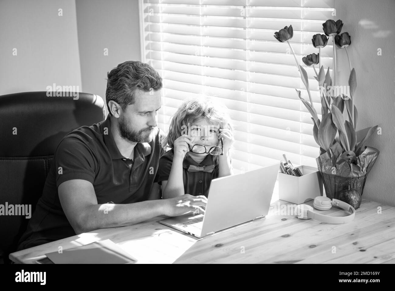 busy dad helping his school son child in glasses study with computer at ...