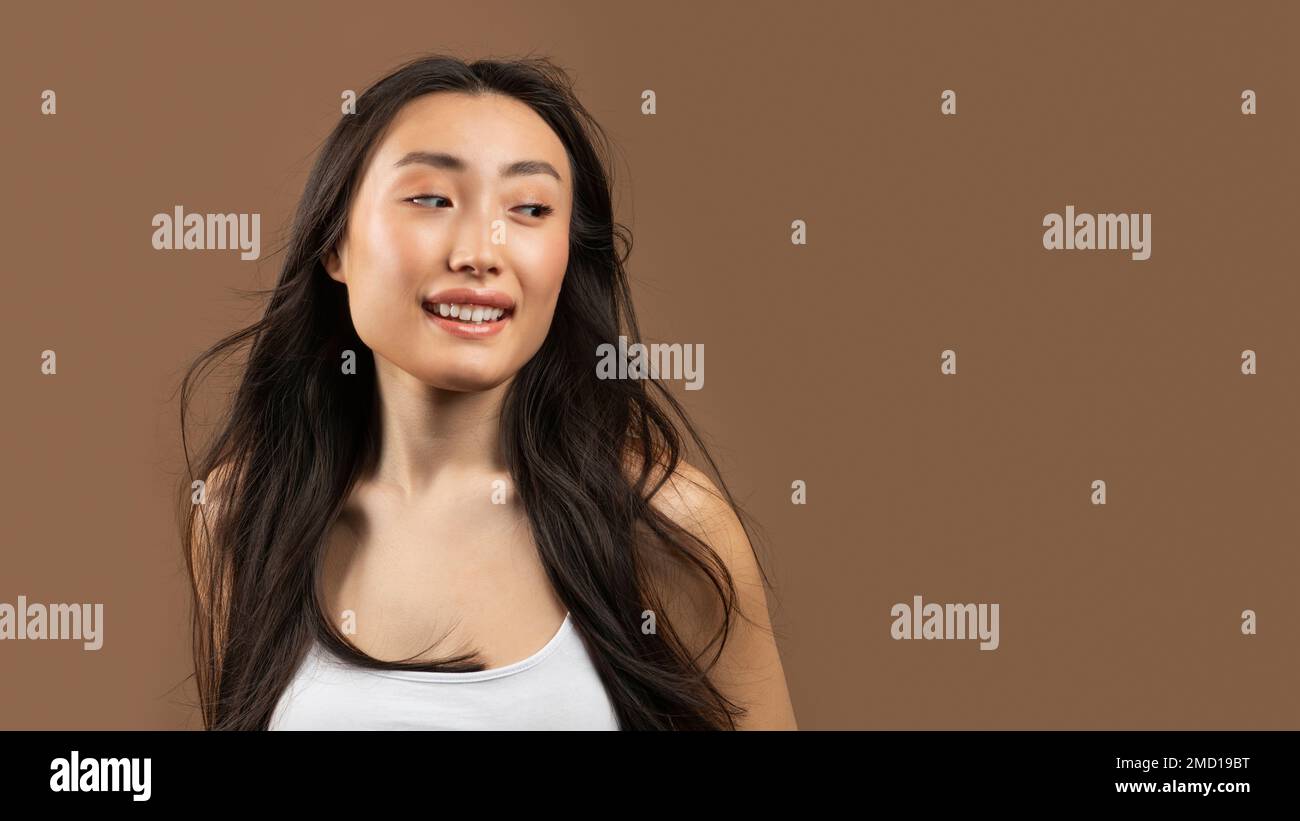 Hair care concept. Portrait of happy asian lady posing with long flying ...