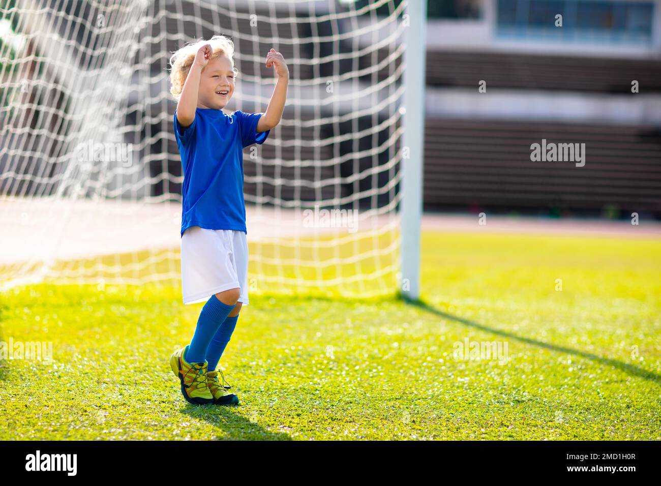 Kids play football on outdoor stadium field. Children score a goal ...