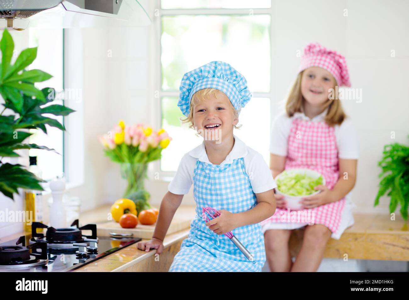 Kids cook in white kitchen. Children cooking at home. Little boy and ...
