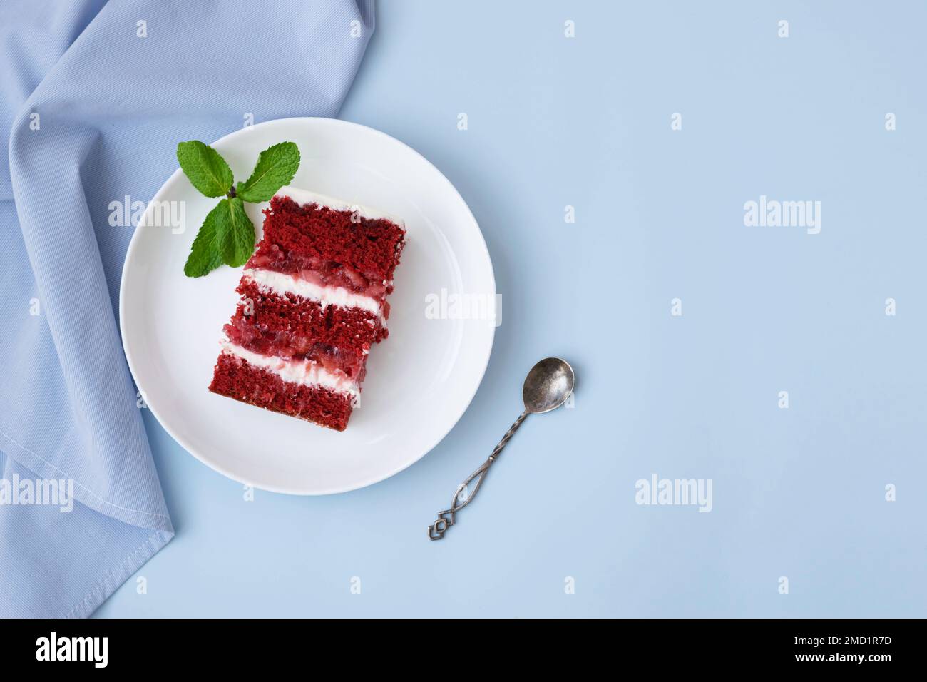 A piece of red velvet sponge cake white plate, pastel blue background ...