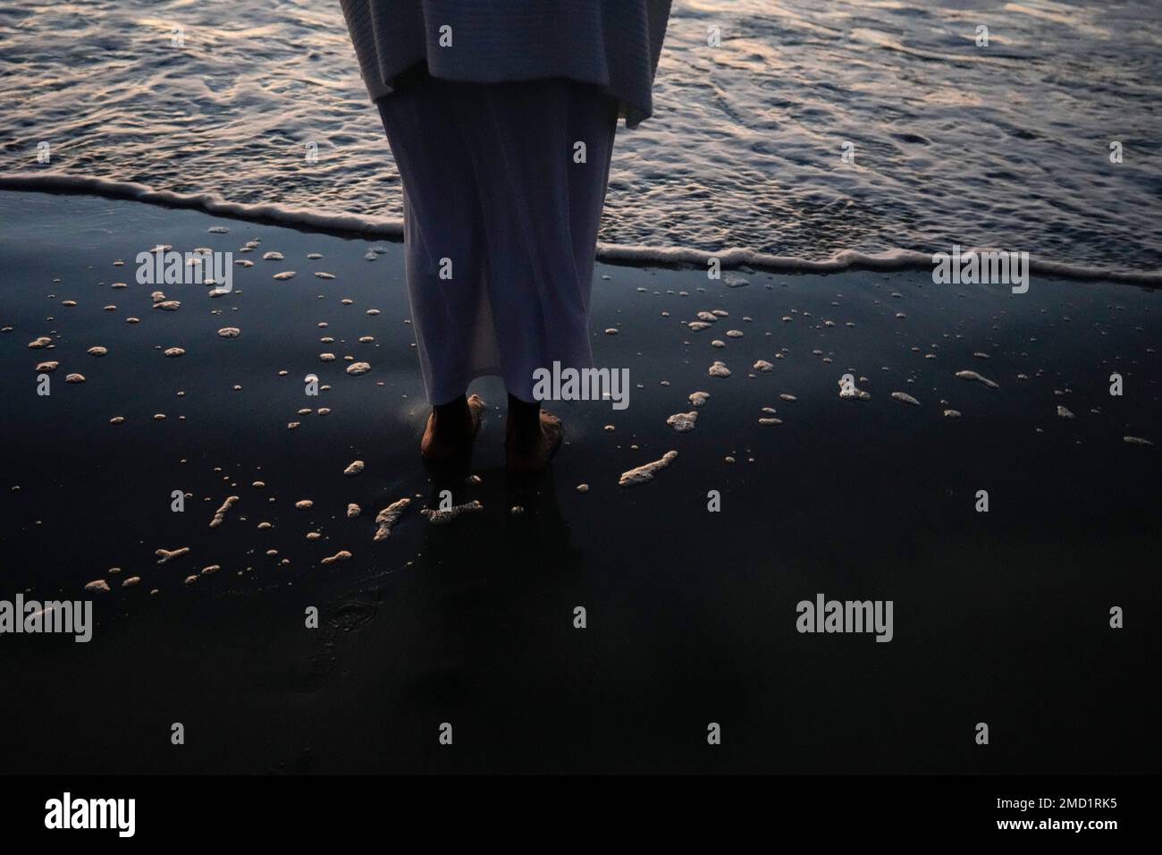 A woman stands in the water at the edge of the Atlantic Ocean during a ...