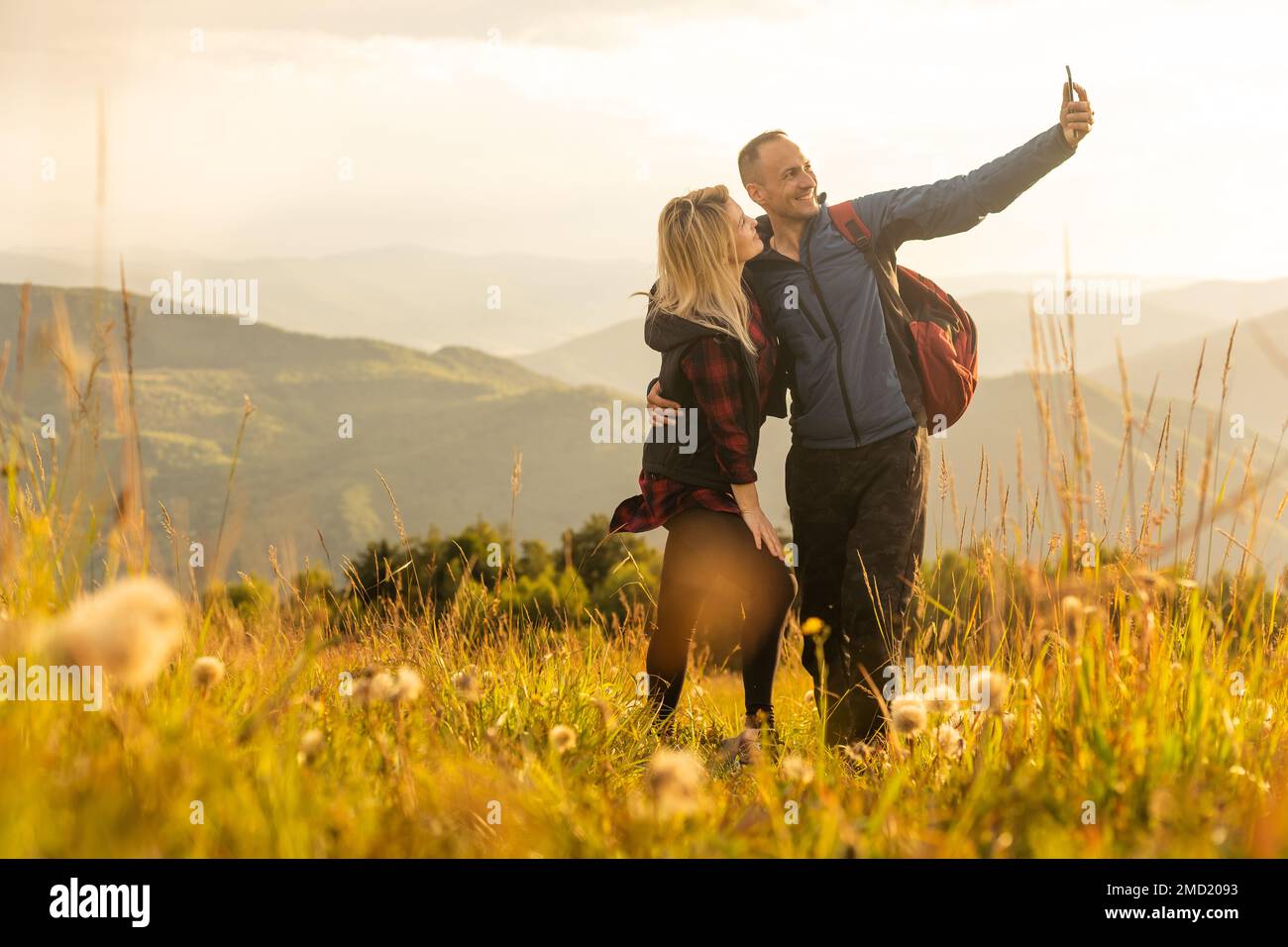Man and woman standing and hugging on the top of the mountain, autumn ...