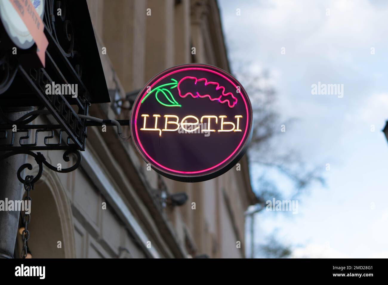 A closeup of a round flower shop sign with a pink neon design and a ...