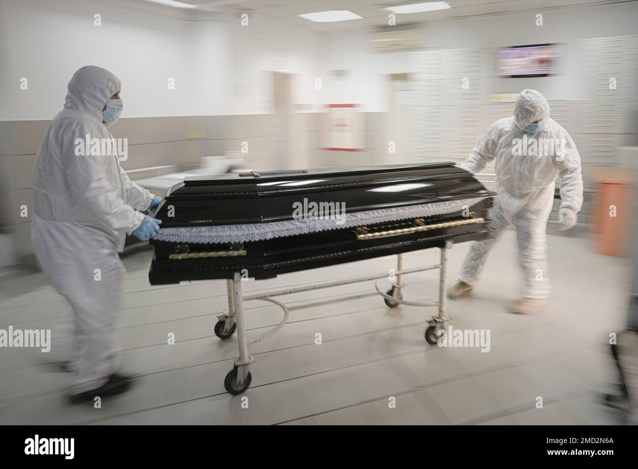Funeral house employees drag a coffin on a trolley as they arrive at ...