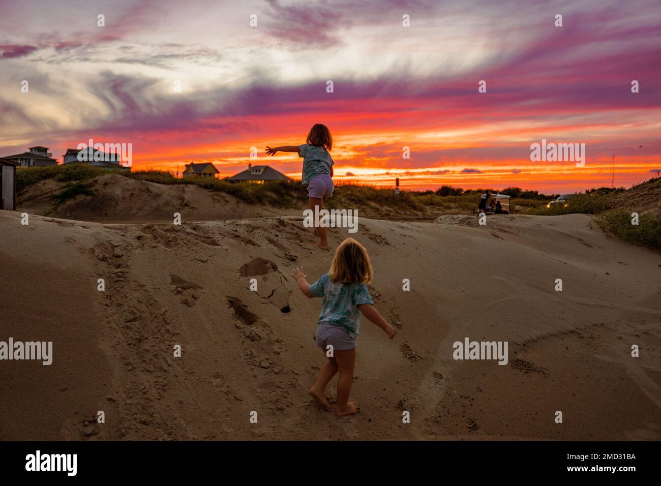 A beautiful shot of two small girls rolling down a sand slide during ...