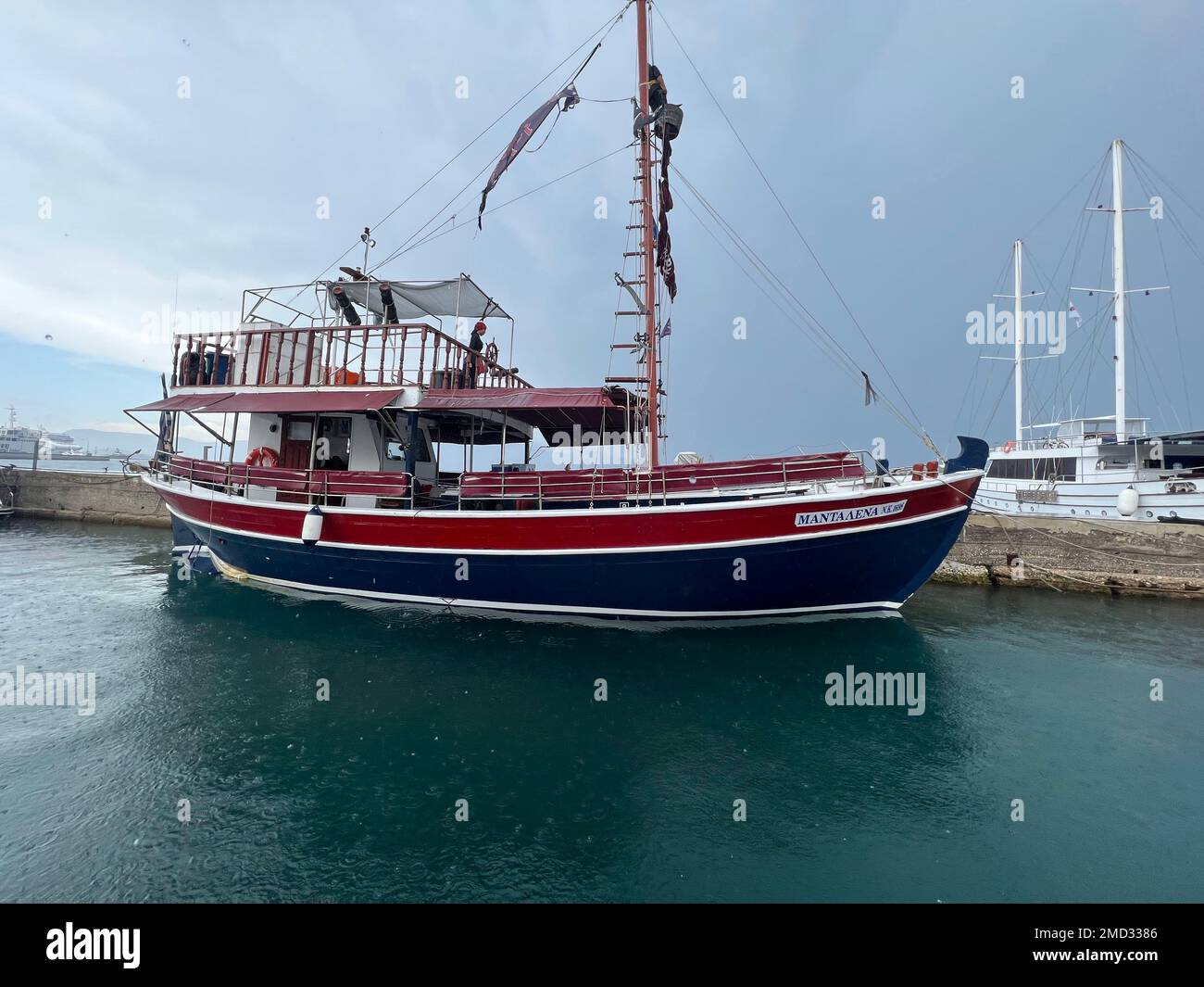 A red and blue ship on the water by the port under the thunderclouds ...