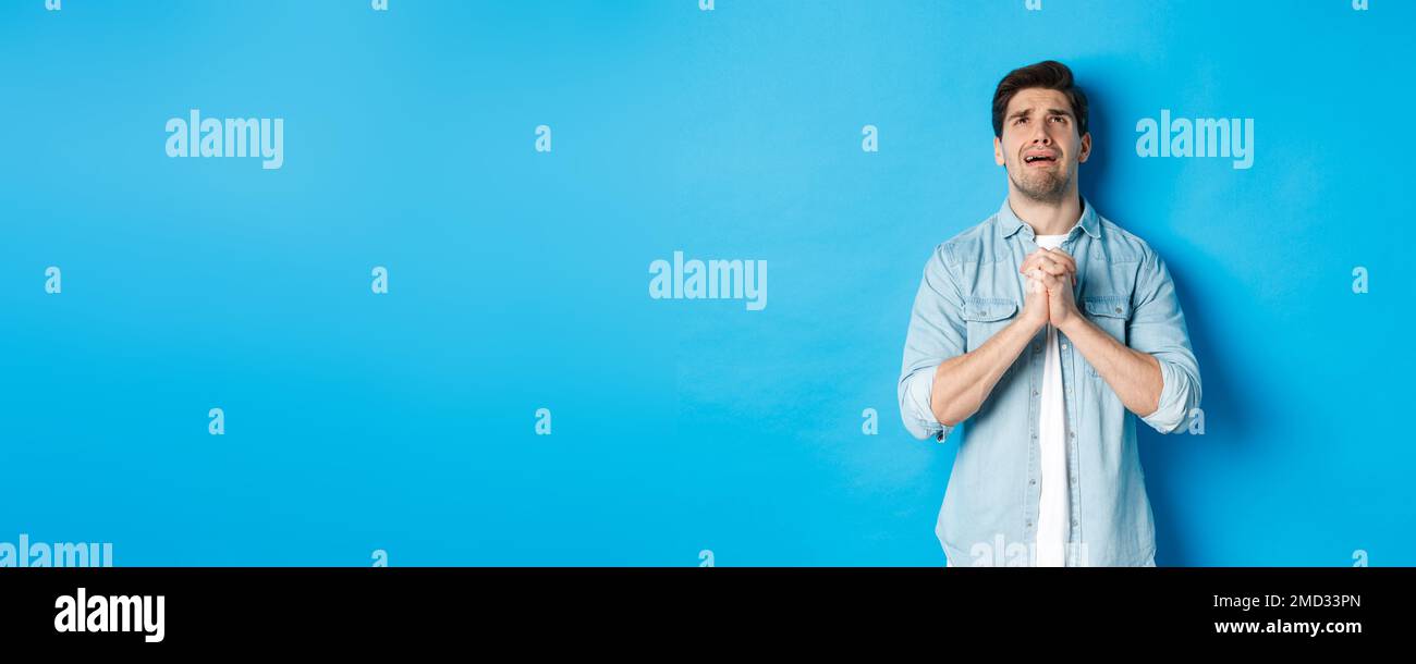 Desperate man begging and crying for help, pleading to god, looking up ...