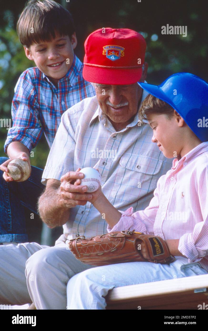 Grand pop sitting outside with his two grandsons, showing them how to ...