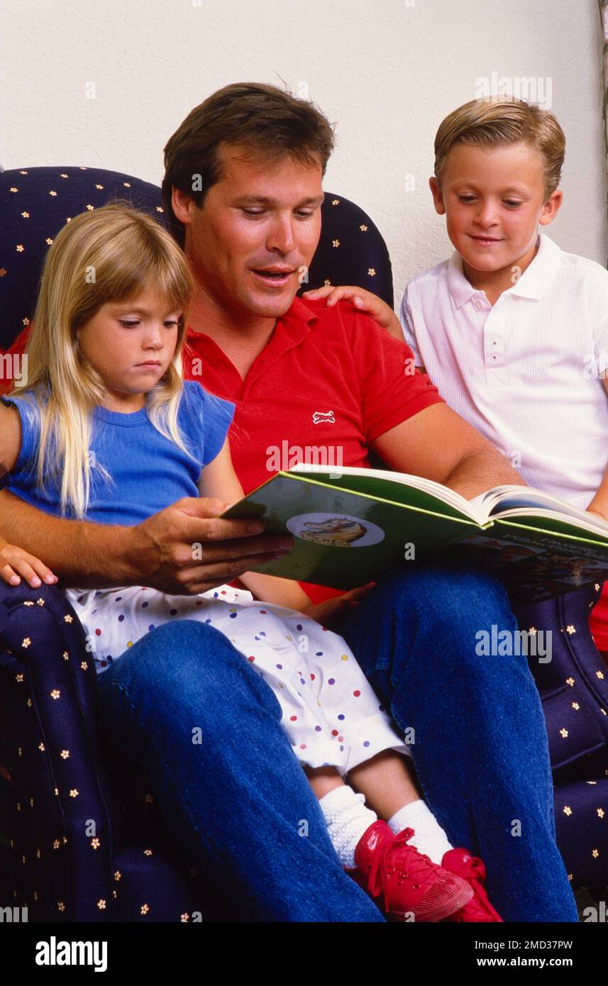 Dad sitting in his easy chair with his daughter on his lap and his son ...