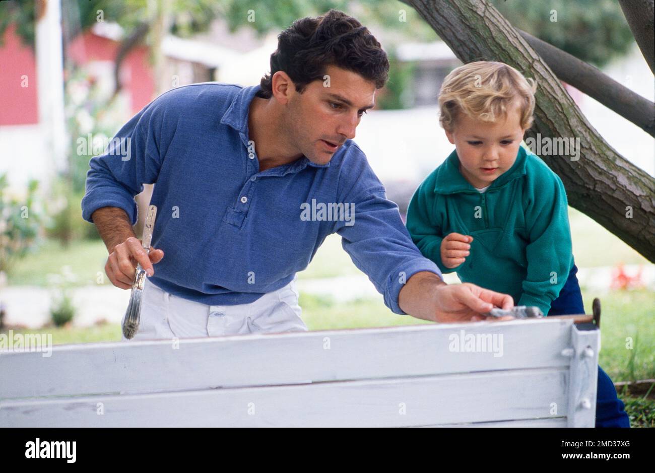 Little blond headed boy helping his daddy paint a bench Stock Photo - Alamy