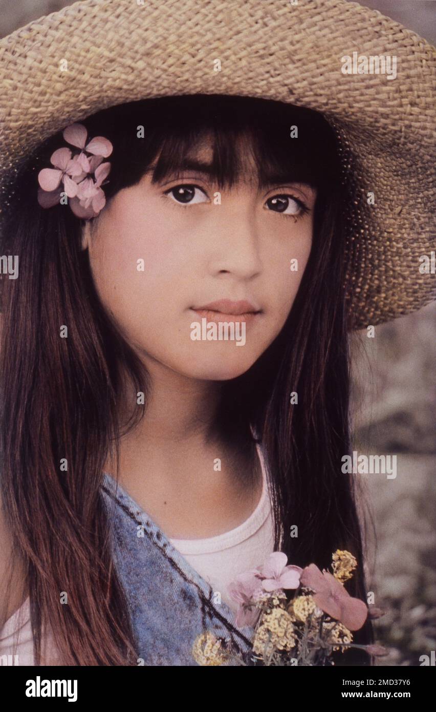 Close-up of a young girl in a straw hat with a flower behind her ear ...