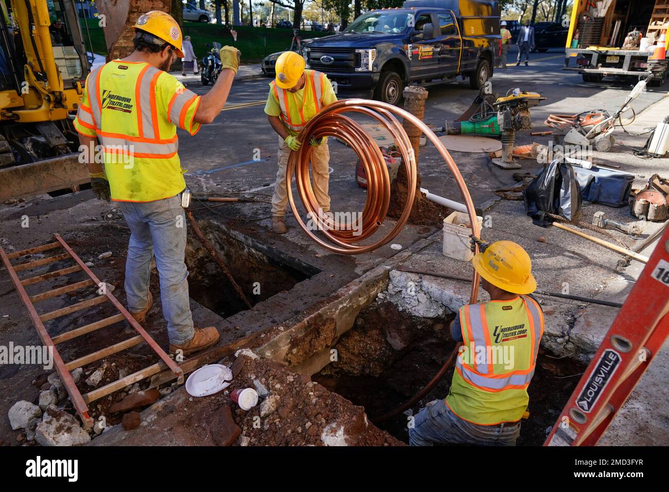 Workmen prepare to replace older water pipes with a new copper one in ...