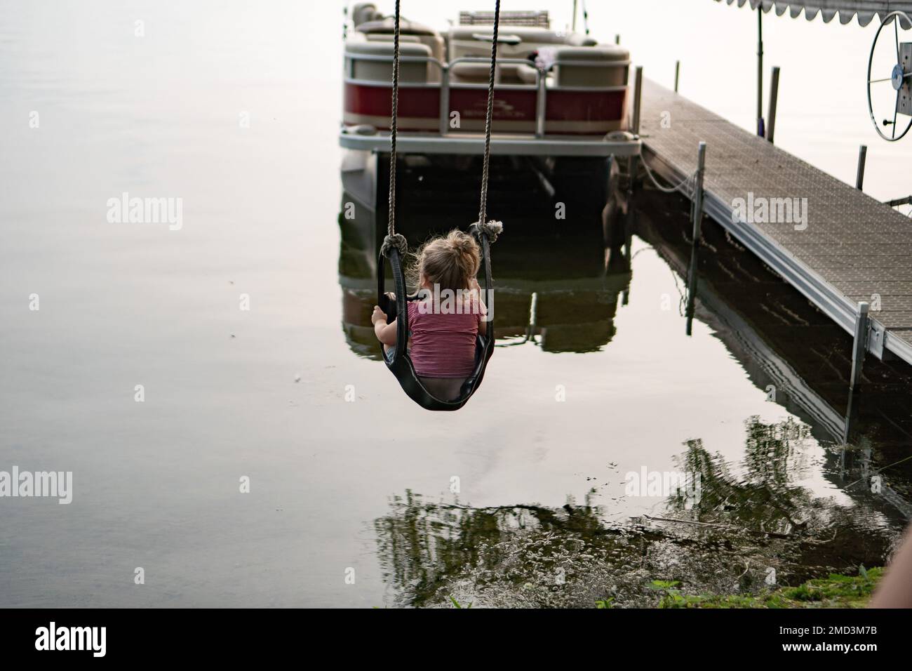 A small girl swinging on a swing over a river Stock Photo - Alamy