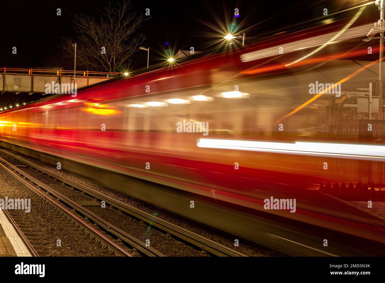 A beautiful shot of a fast moving red train at night at a station in ...